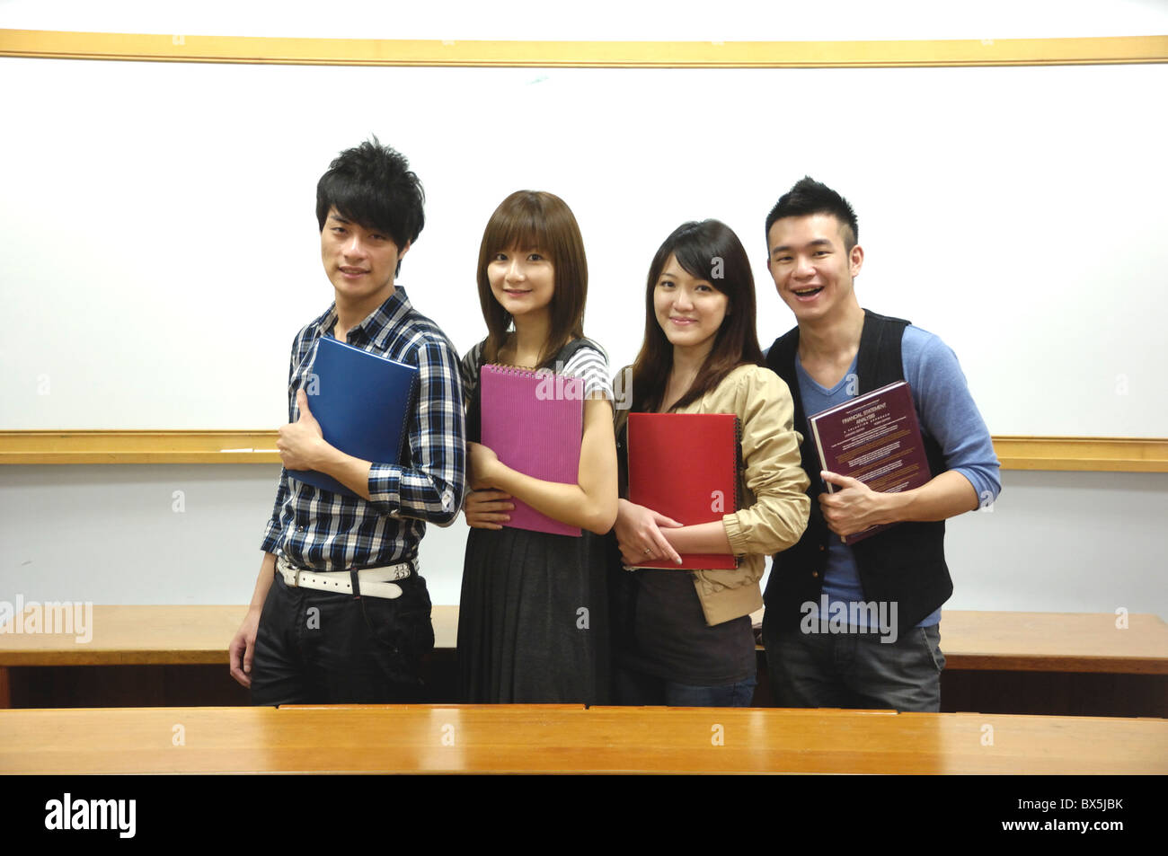 University students holding books and smiling in a classroom Stock ...