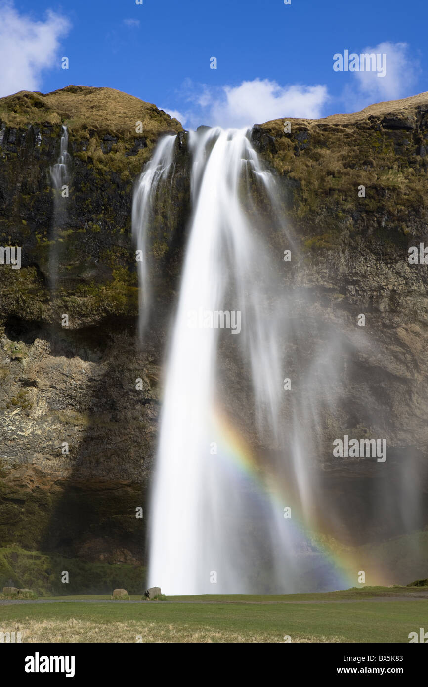 Seljalandsfoss Waterfall tumbling over towering cliffs in bright ...