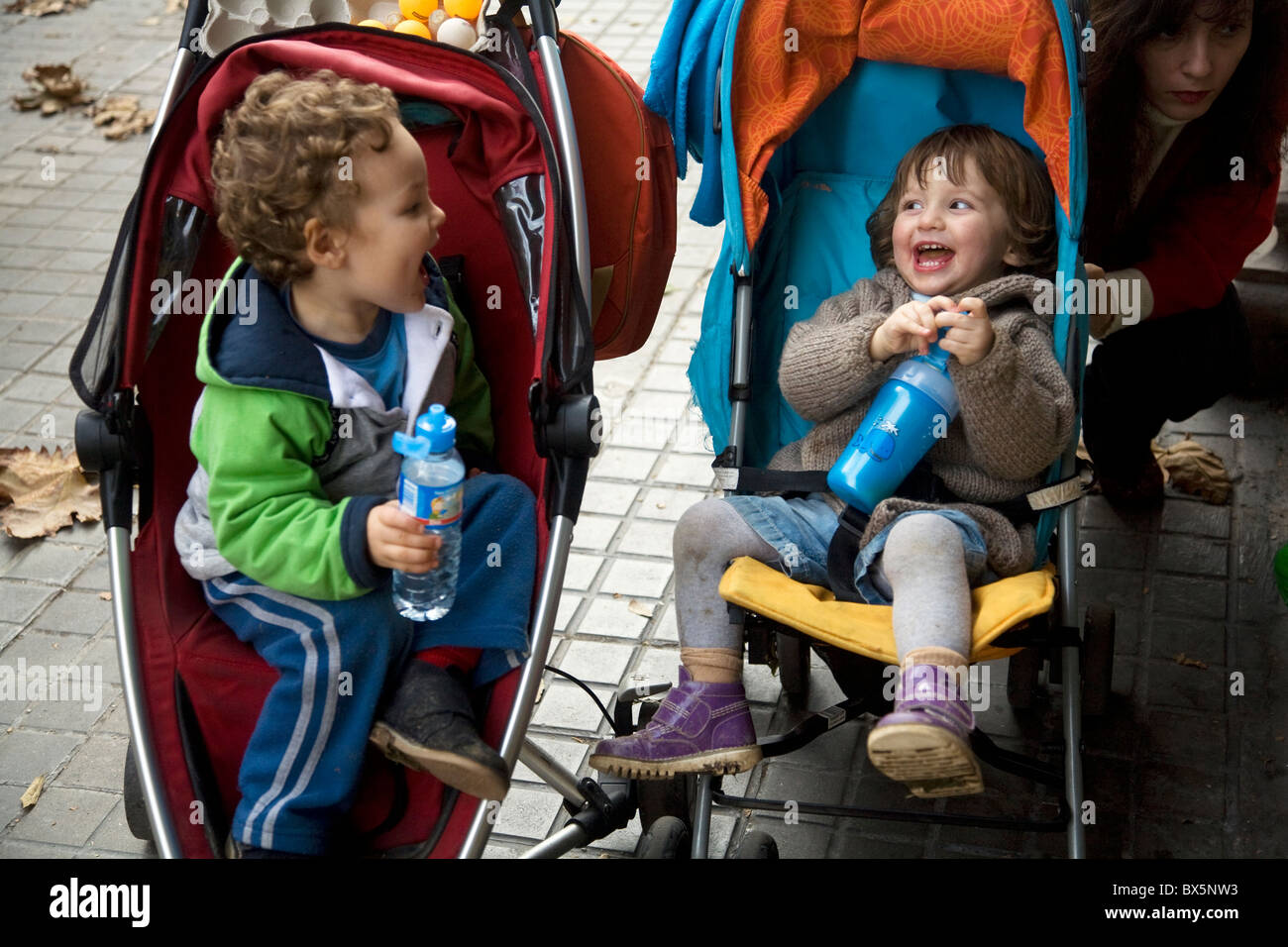 Two boys in their push chairs talk and laugh together Stock Photo - Alamy
