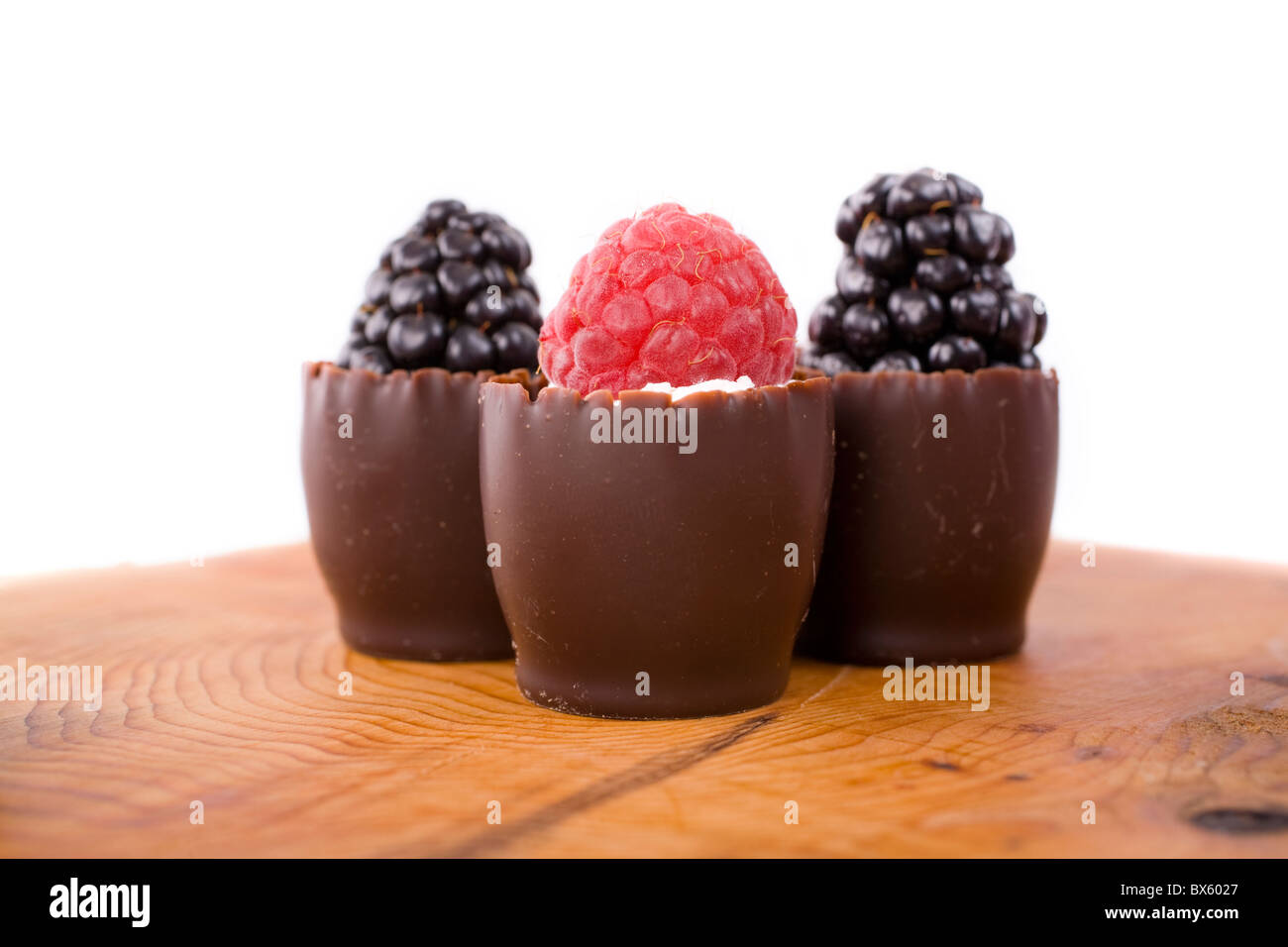 Three mini-chocolate cups filled with cream and topped with raspberry ...