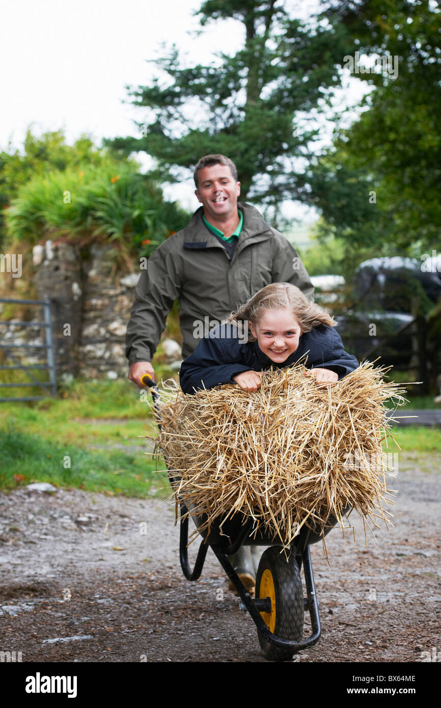 Girl being pushed in wheel barrow Stock Photo - Alamy