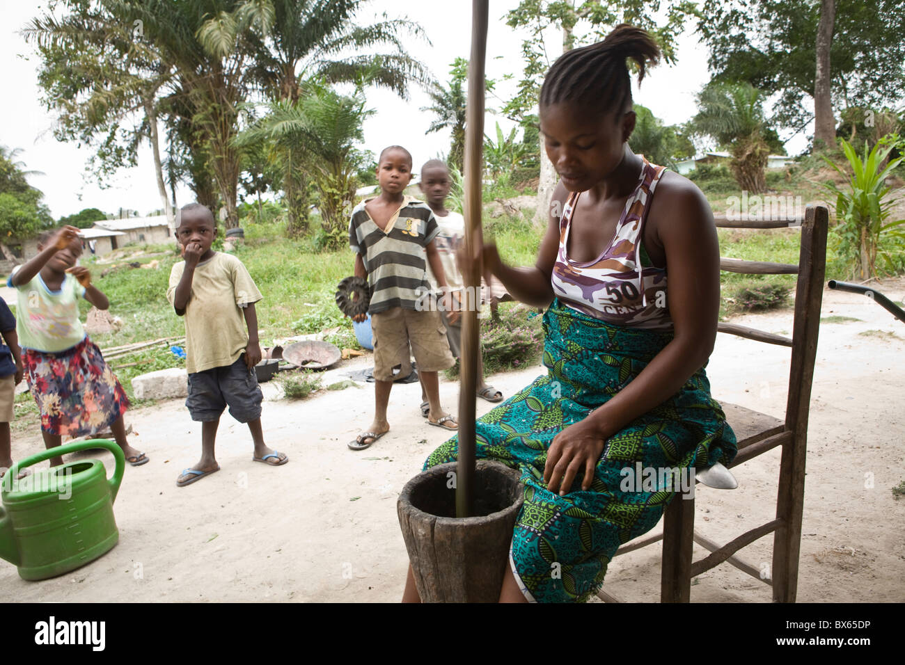 A young woman grinds cassava flour in Kakata, Liberia, West Africa ...