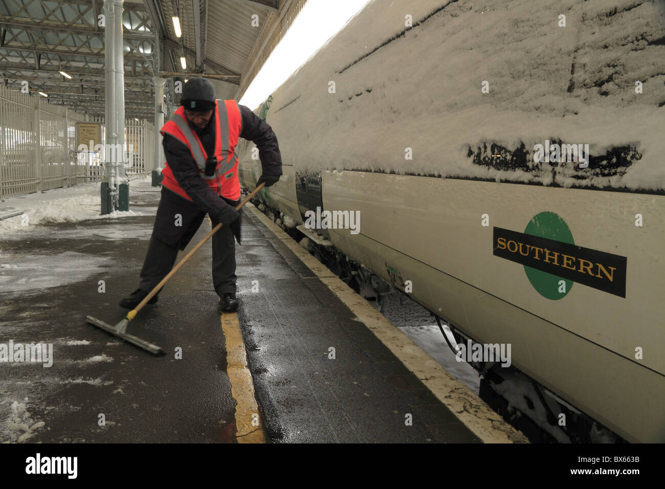 A worker clears the platform of snow at Eastbourne Railway Station ...