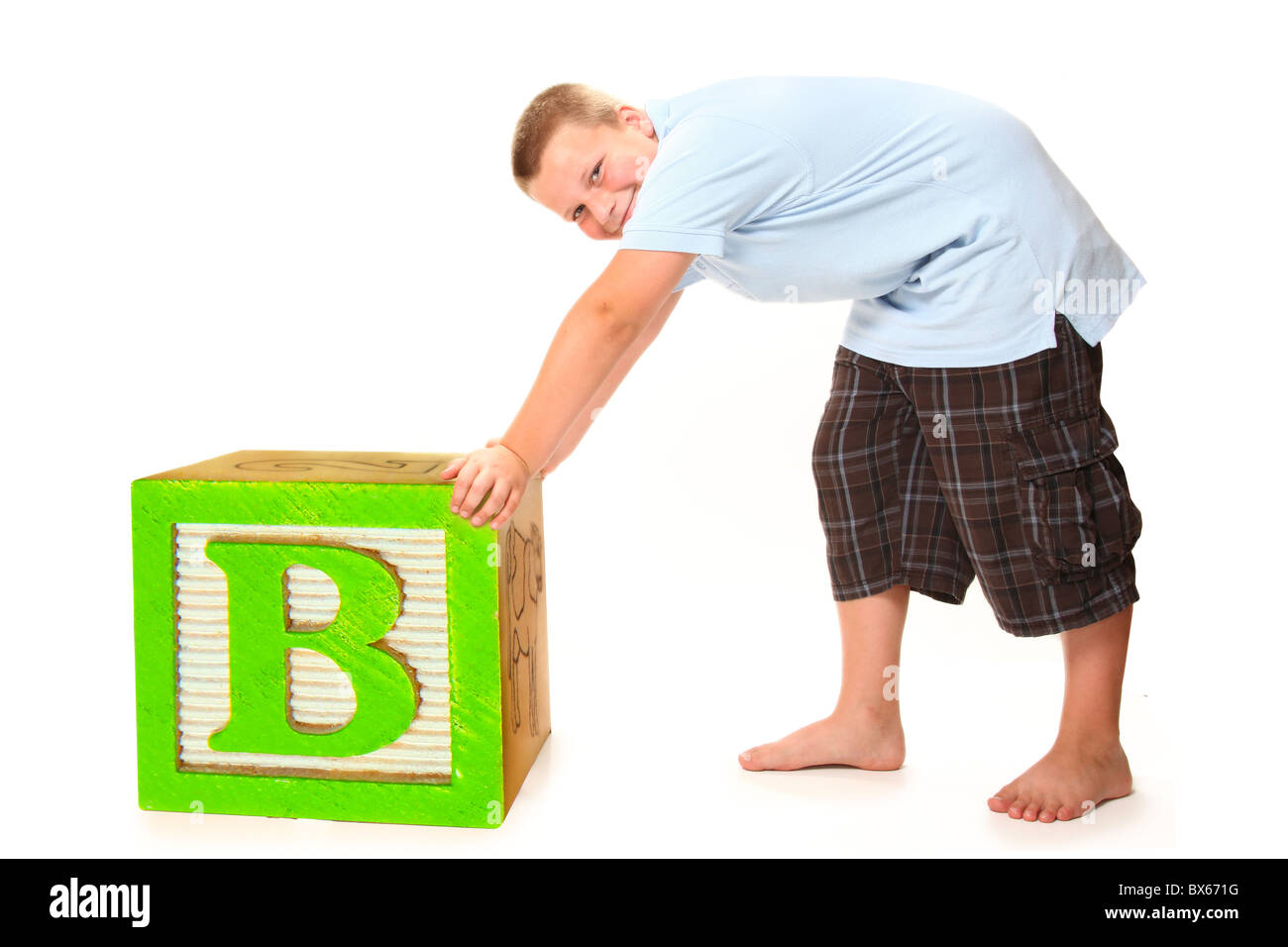 Handsome nine year old boy pushing giant alphabet block over white ...