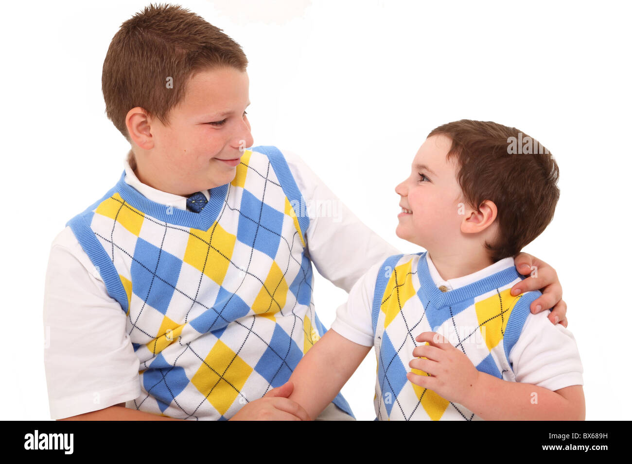 Two handsome brothers smiling at each other over white. Dressed alike ...
