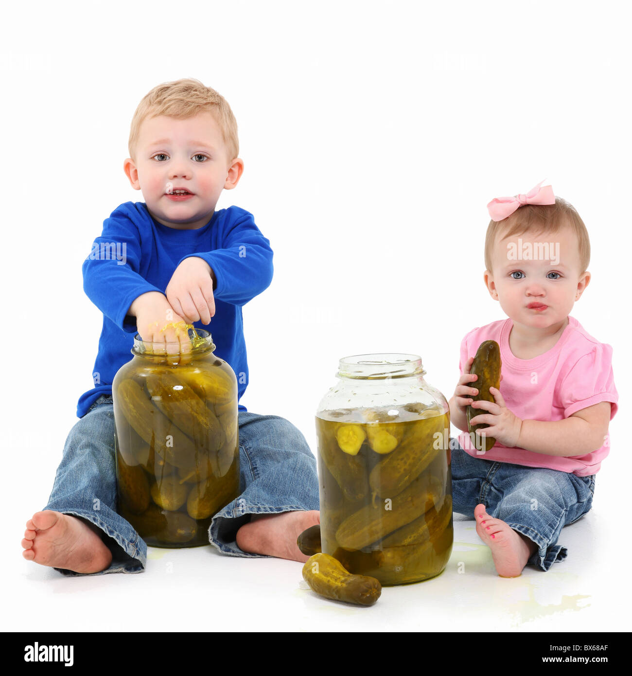 Adorable siblings, boy and girl, eating from giant pickle jars over ...