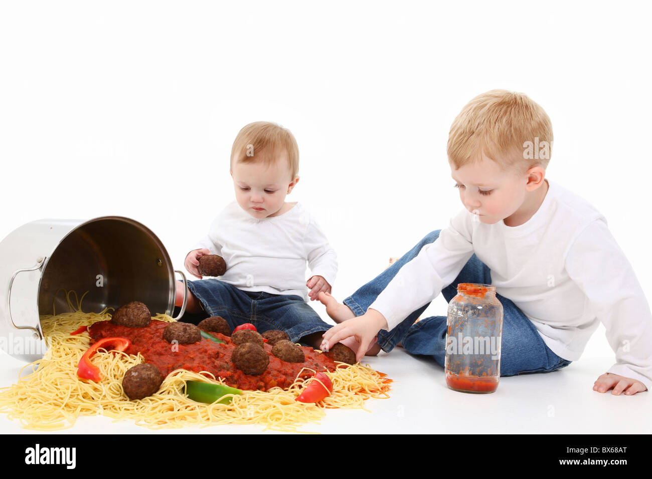 Adorable brother and sister eating from speghetti mess on floor over ...