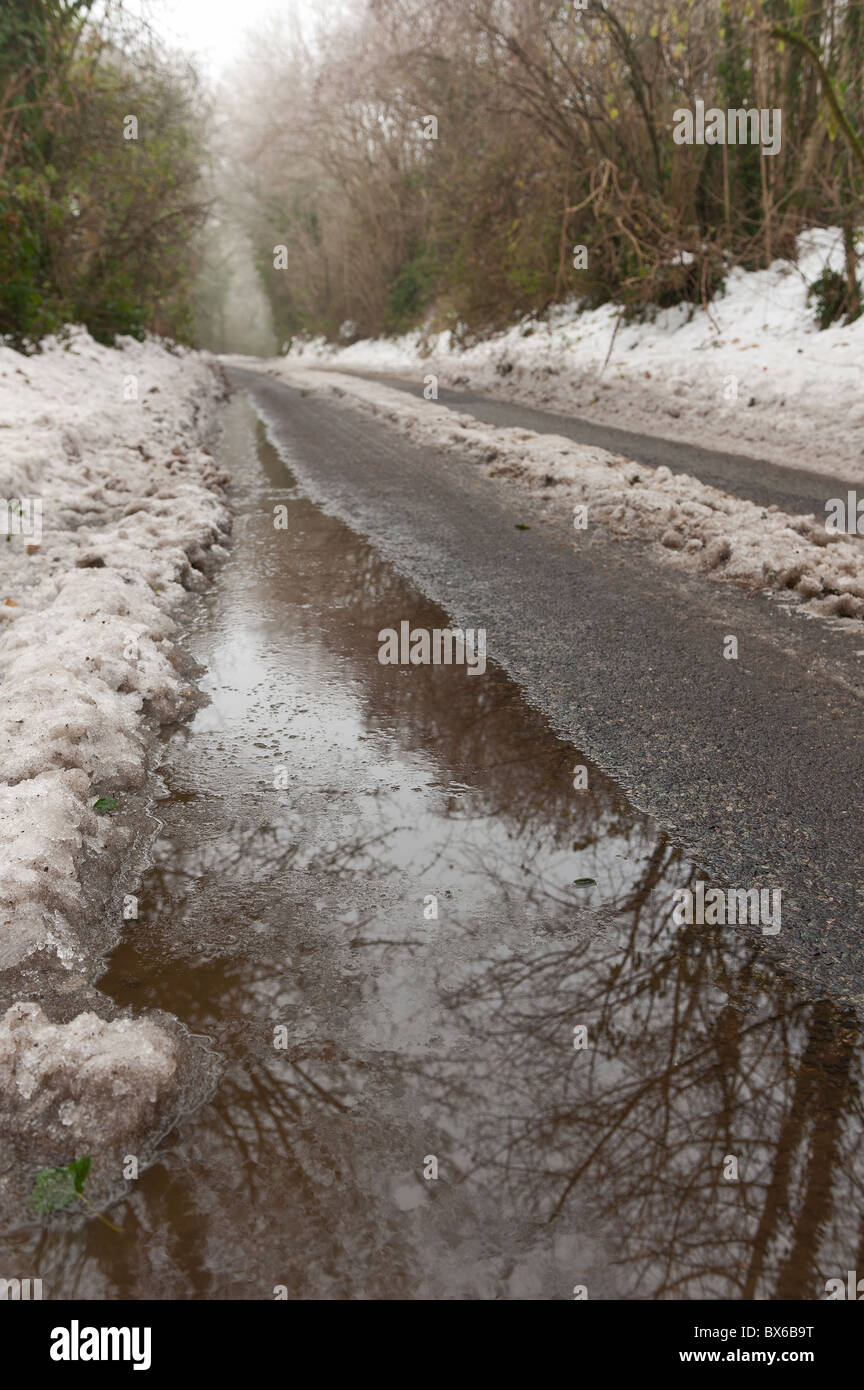 Potholes and melting snow runoff in a country road caused by snow and ...