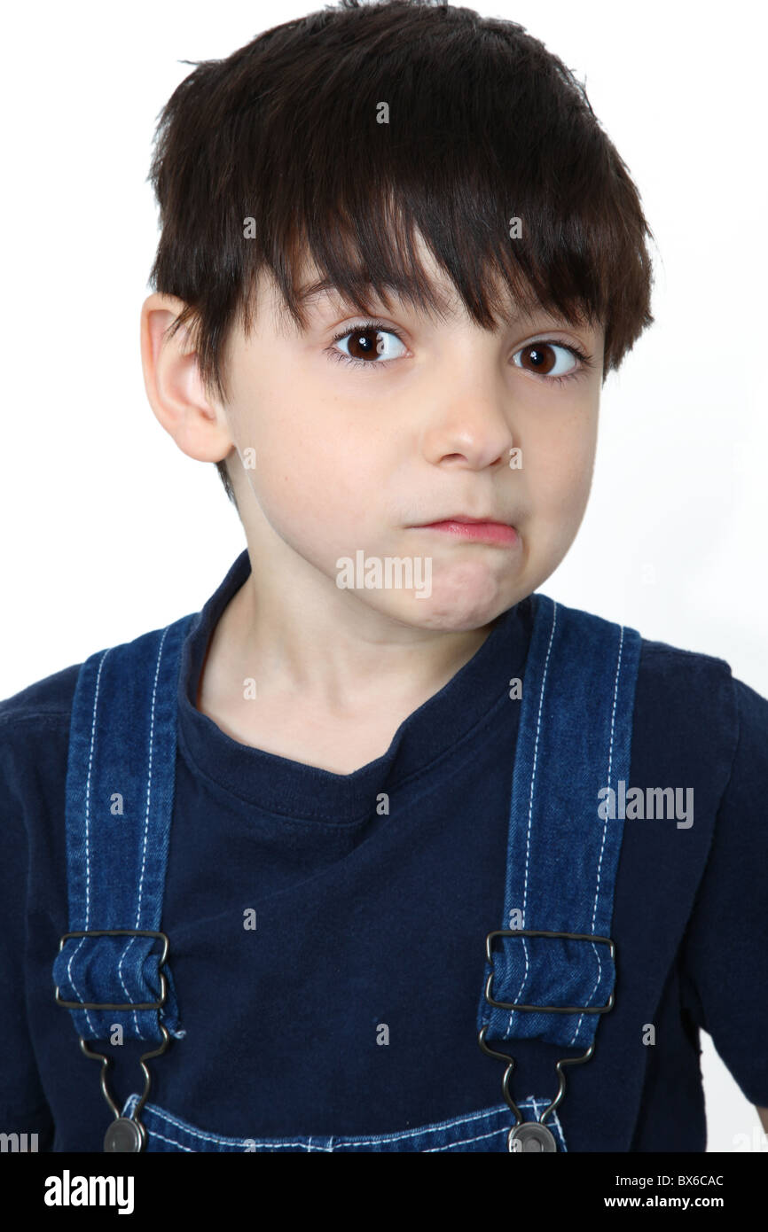 Adorable six year old caucasian boy in overalls making silly faces with ...