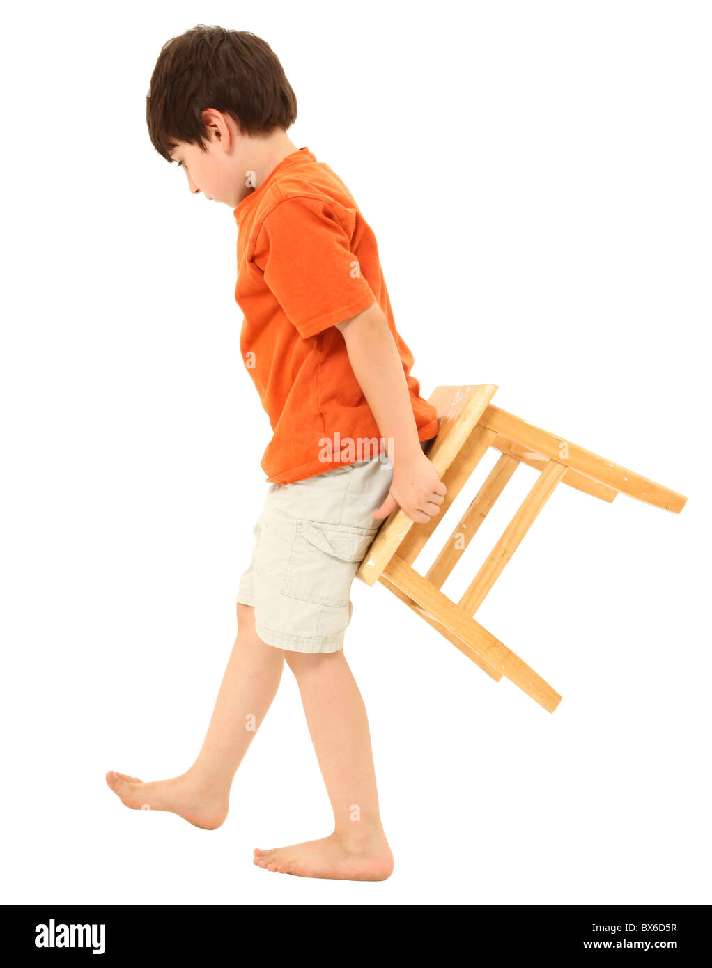 Adorable seven year old boy carrying a stool behind him Stock Photo - Alamy