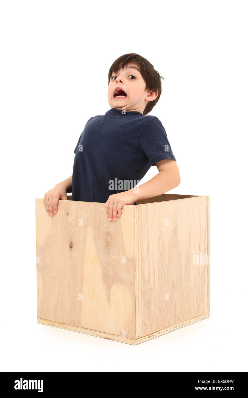 Adorable 7 year old french american boy in wooden box scared over white ...