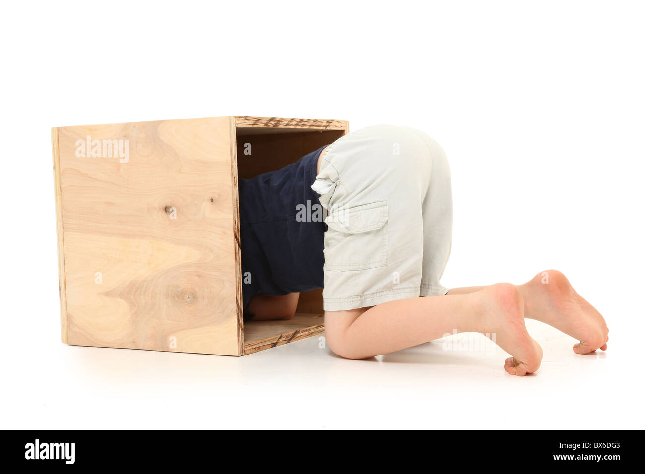 Back end of seven year old boy sticking out of wooden box over white ...