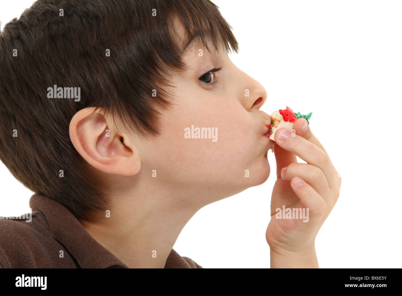 Adorable 7 year old french american boy eating small bakery treat over ...