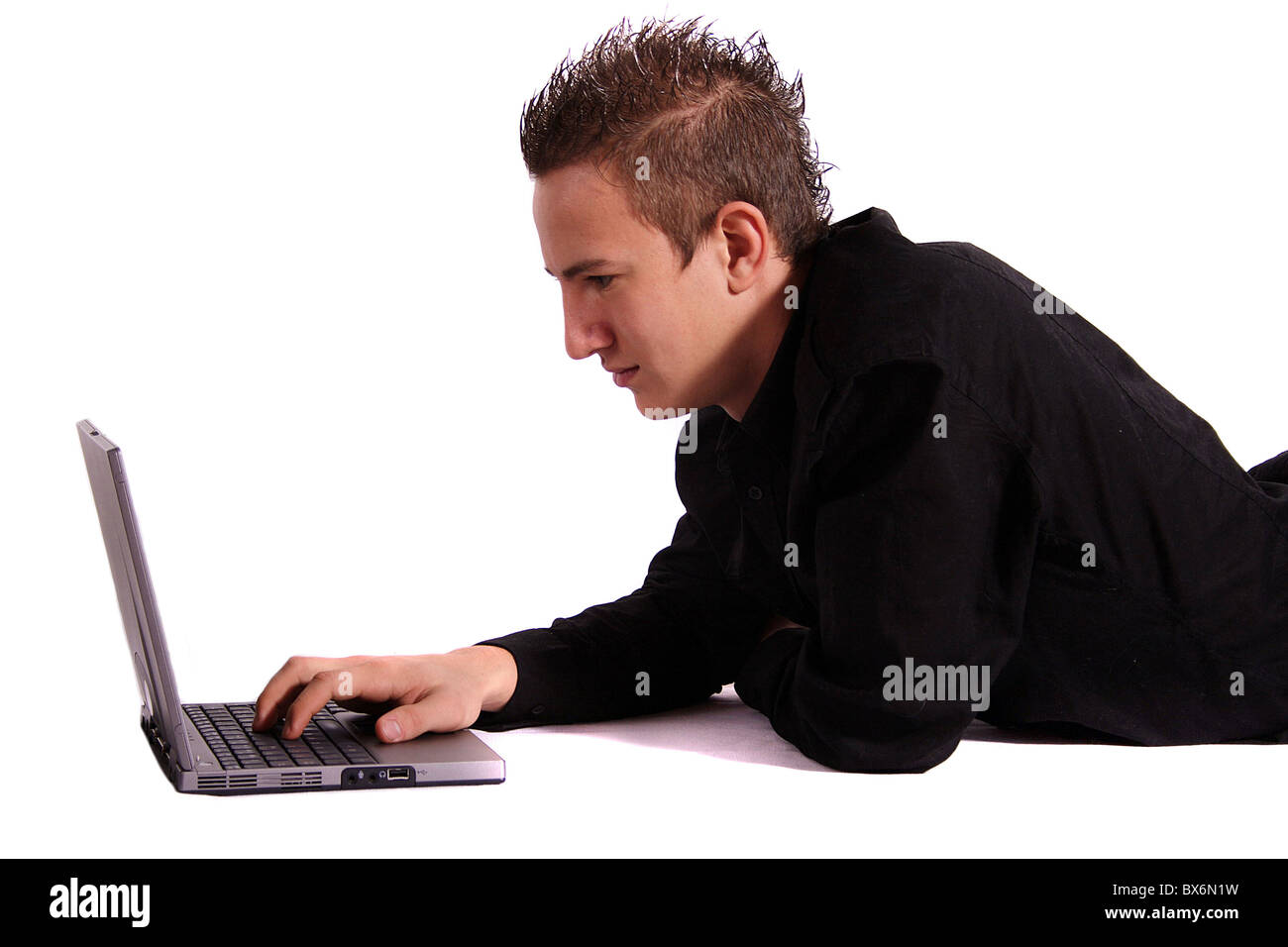 A young handsome man lying on the floor and surfing the internet with ...