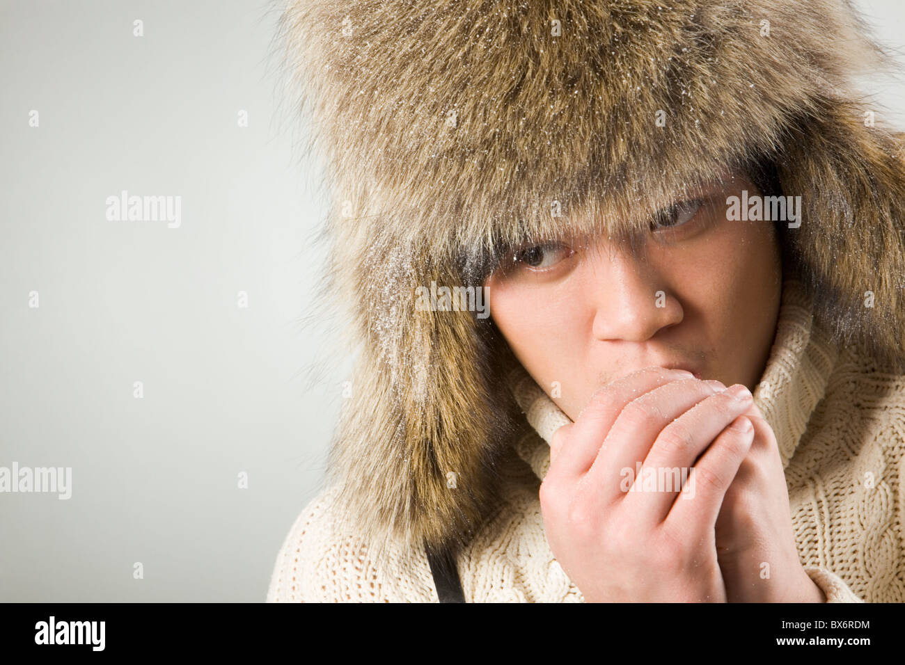 Portrait of cold man in fur hat and knitted sweater warming up his ...