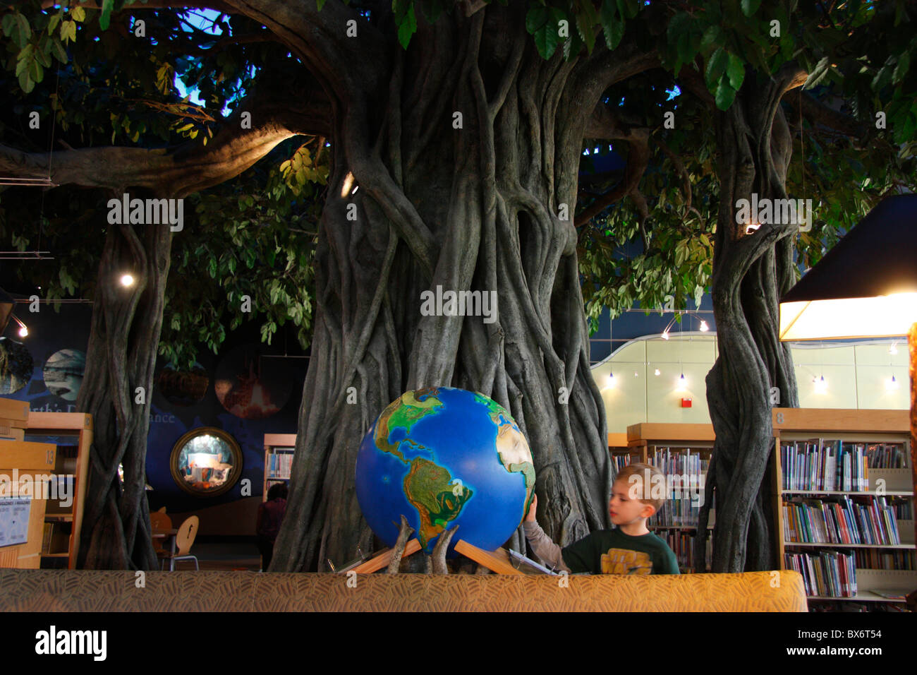 A boy looks at he globe under the Banyan tree in the children's library ...