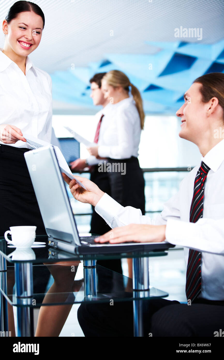 Portrait of busy chief taking documents from secretary hands while ...