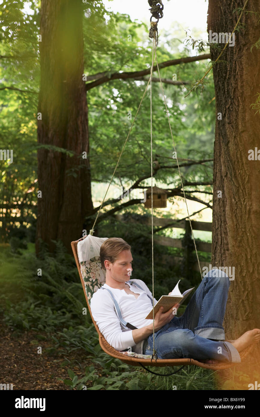 Young man reading in hammock Stock Photo - Alamy