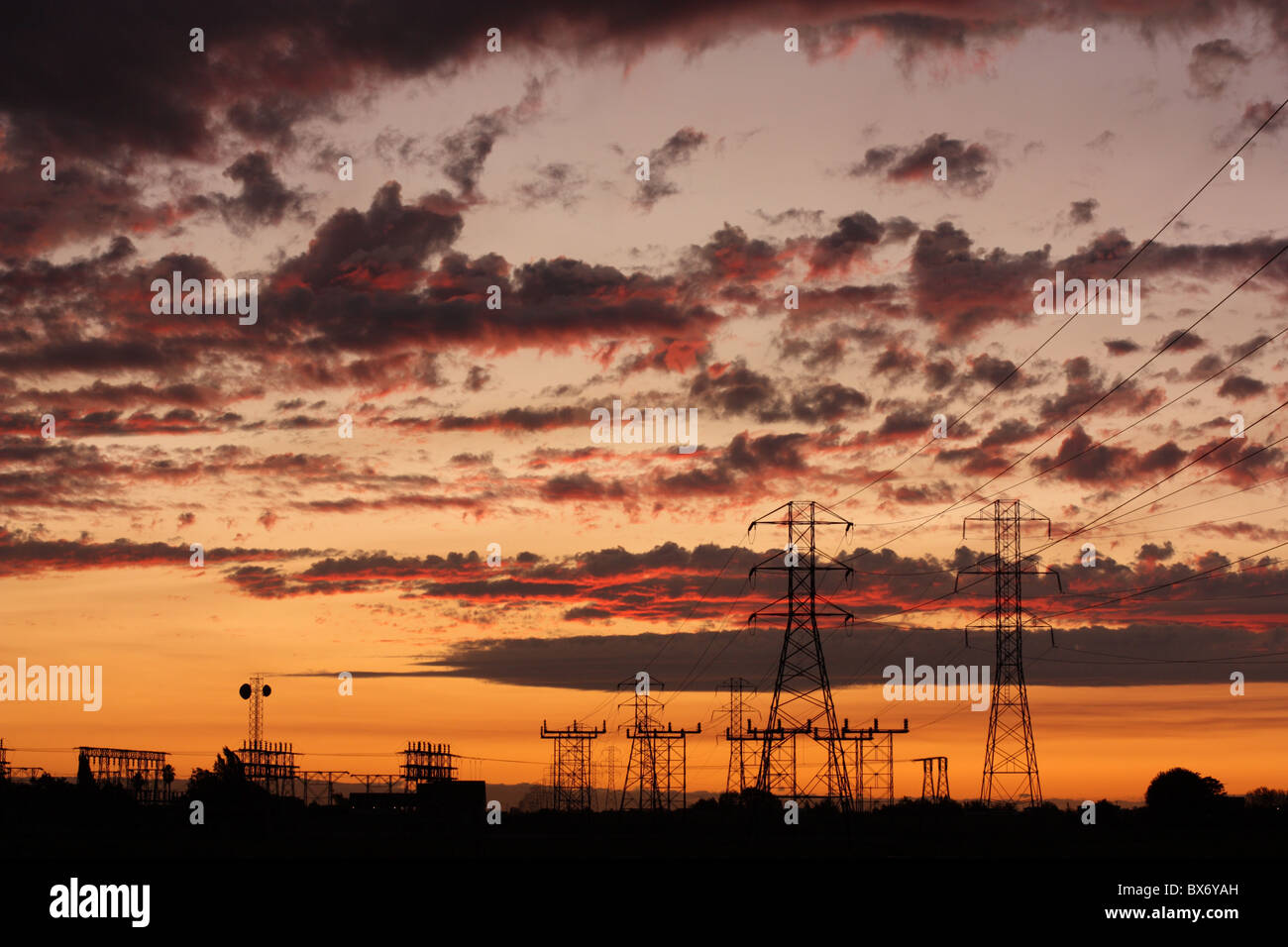 Transmission towers and power lines silhouetted against a dramatic ...