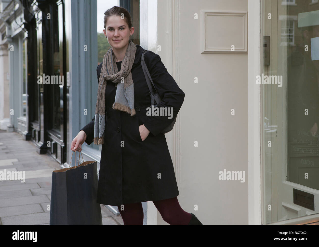 Woman leaving shop with bag Stock Photo - Alamy