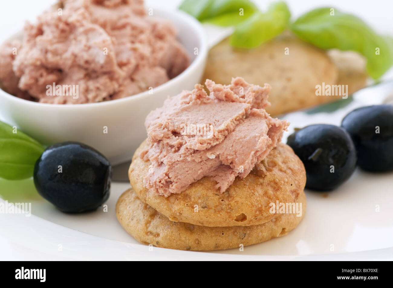 Meat paste with cracker and olives as closeup on white background Stock ...
