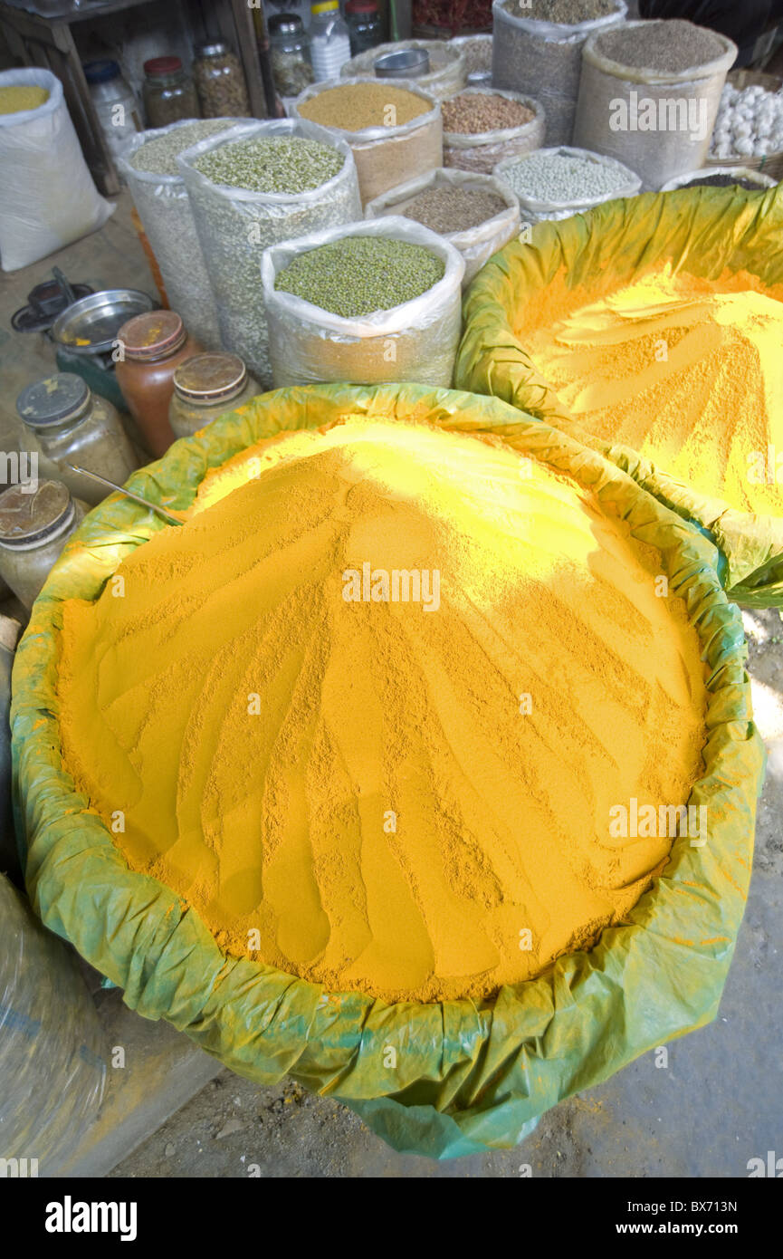 Spice market stall with large bowls of turmeric powder in morning ...
