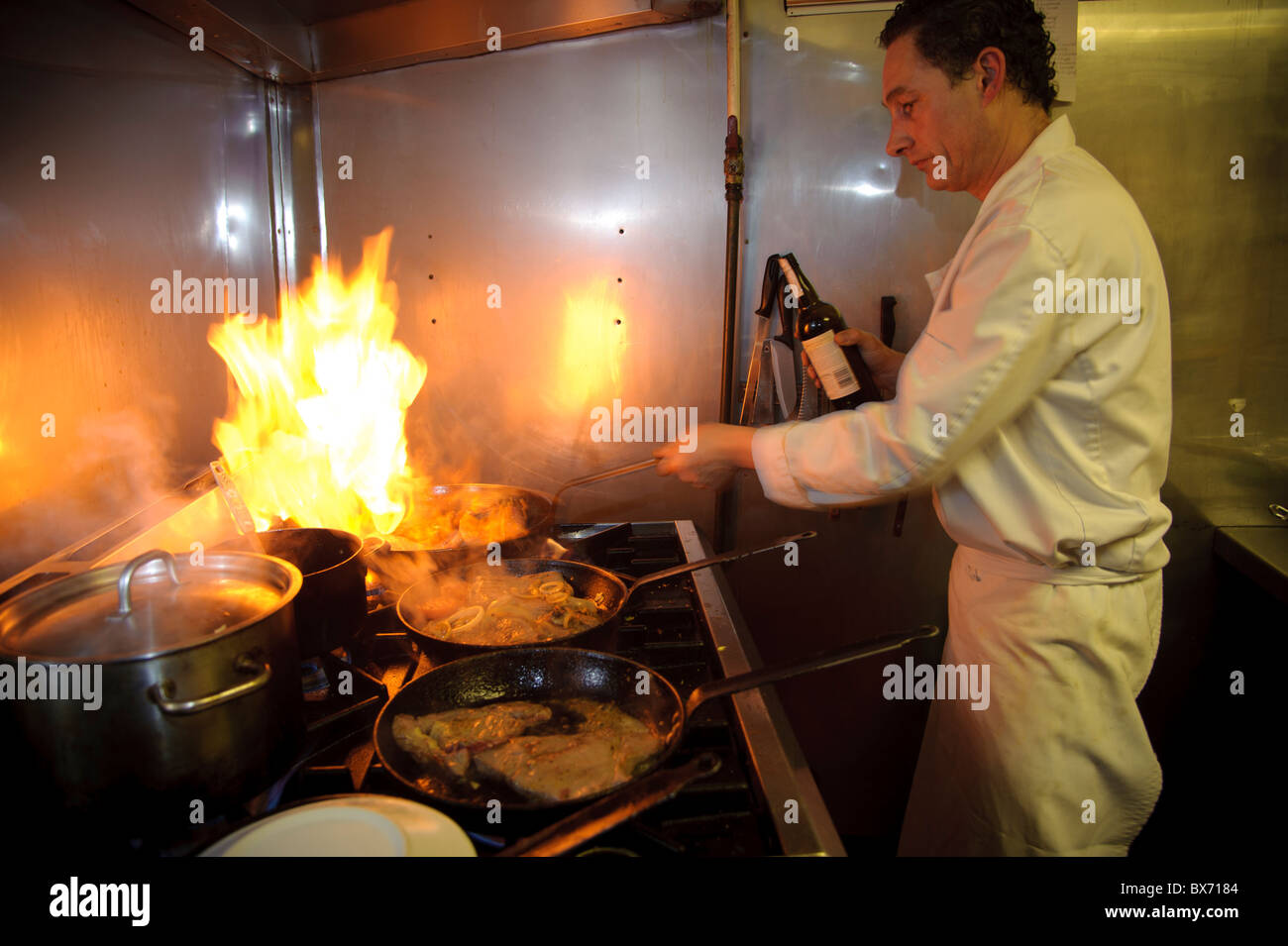 A chef in a restaurant kitchen cooking flambe steak, UK Stock Photo - Alamy
