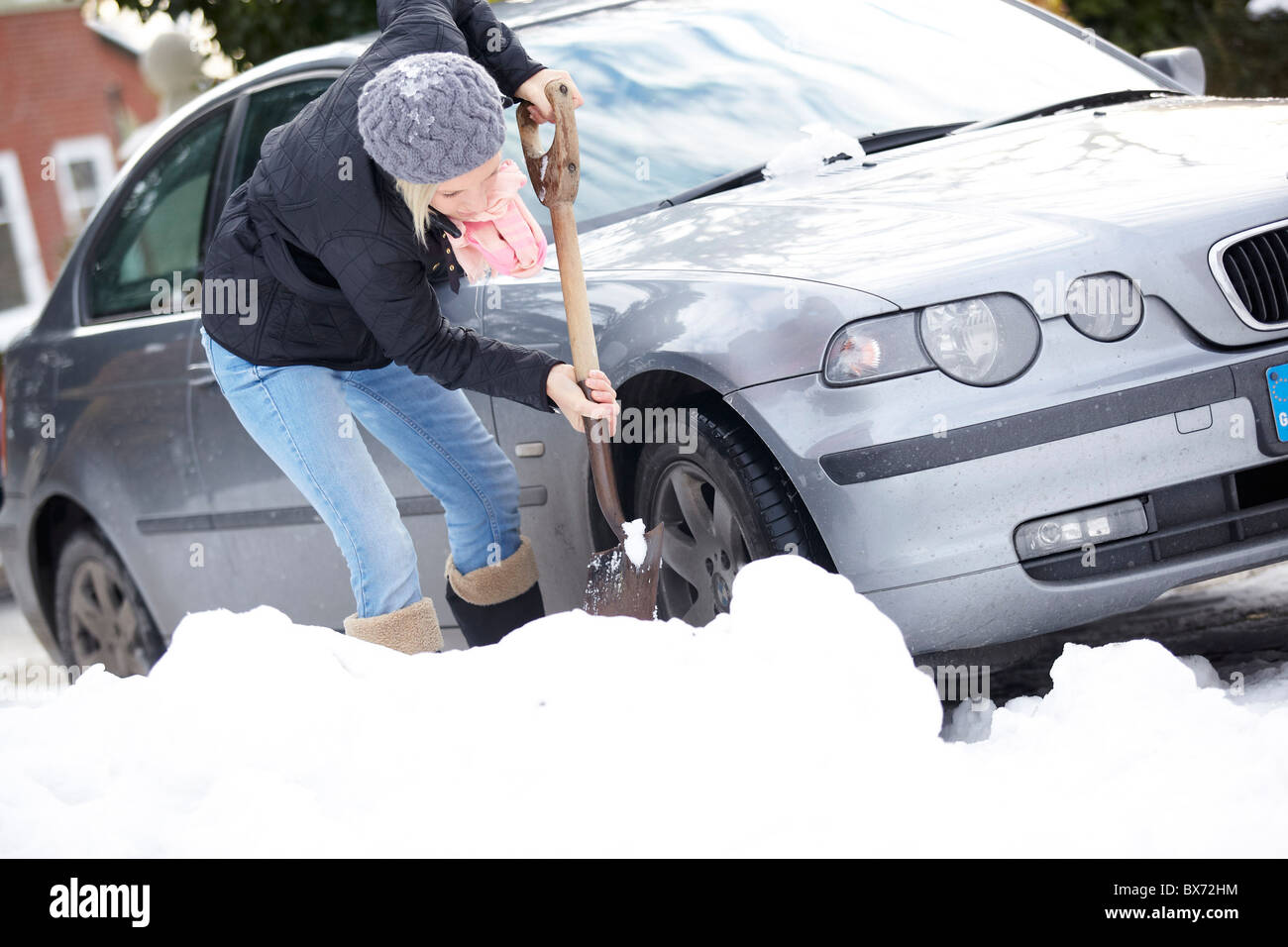 Woman digging out car from snow Stock Photo - Alamy