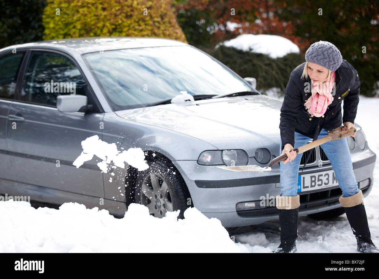Woman digging out car from snow Stock Photo - Alamy