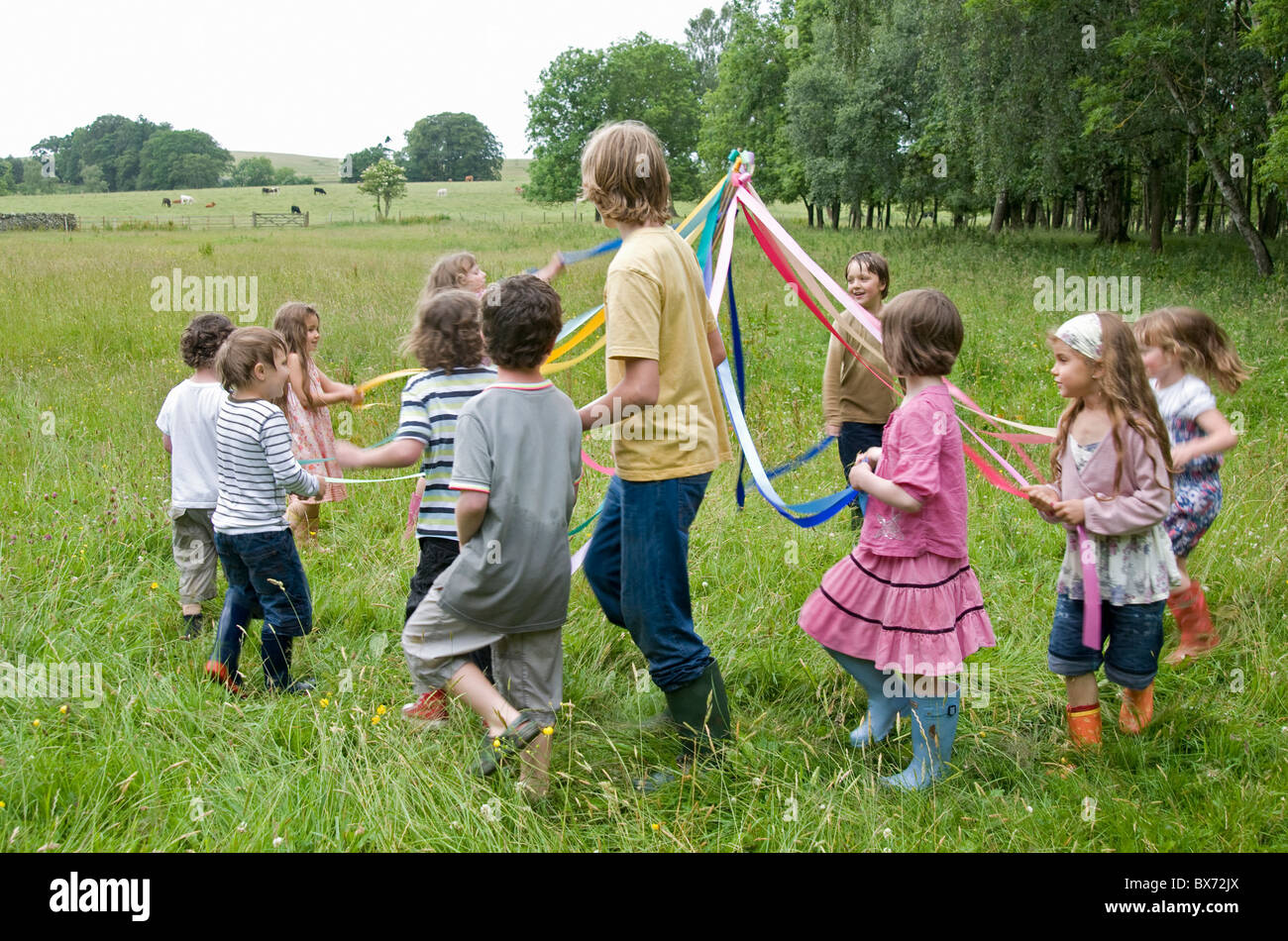 Kids dancing round maypole in meadow Stock Photo - Alamy