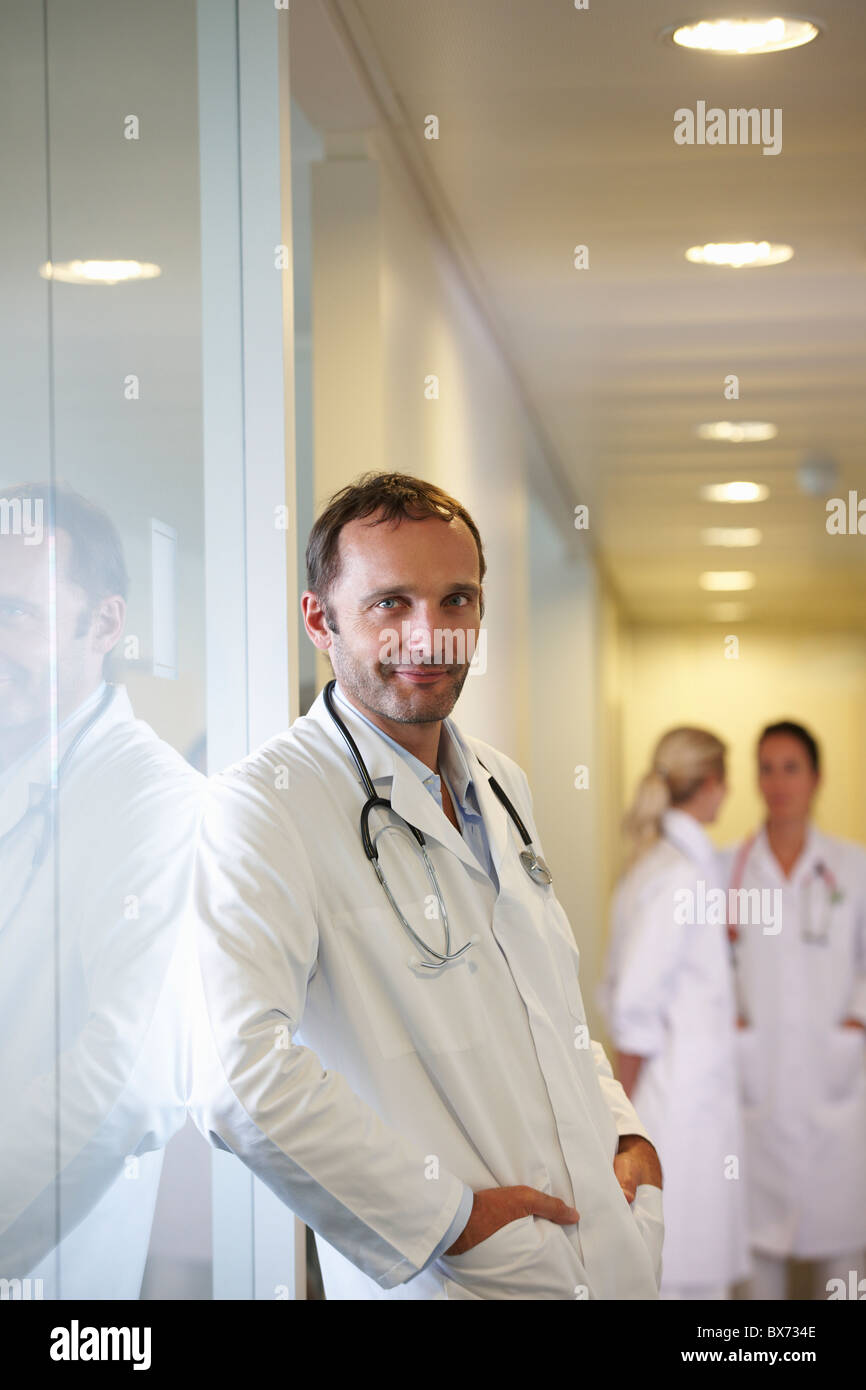 Doctor against a window, smiling Stock Photo - Alamy