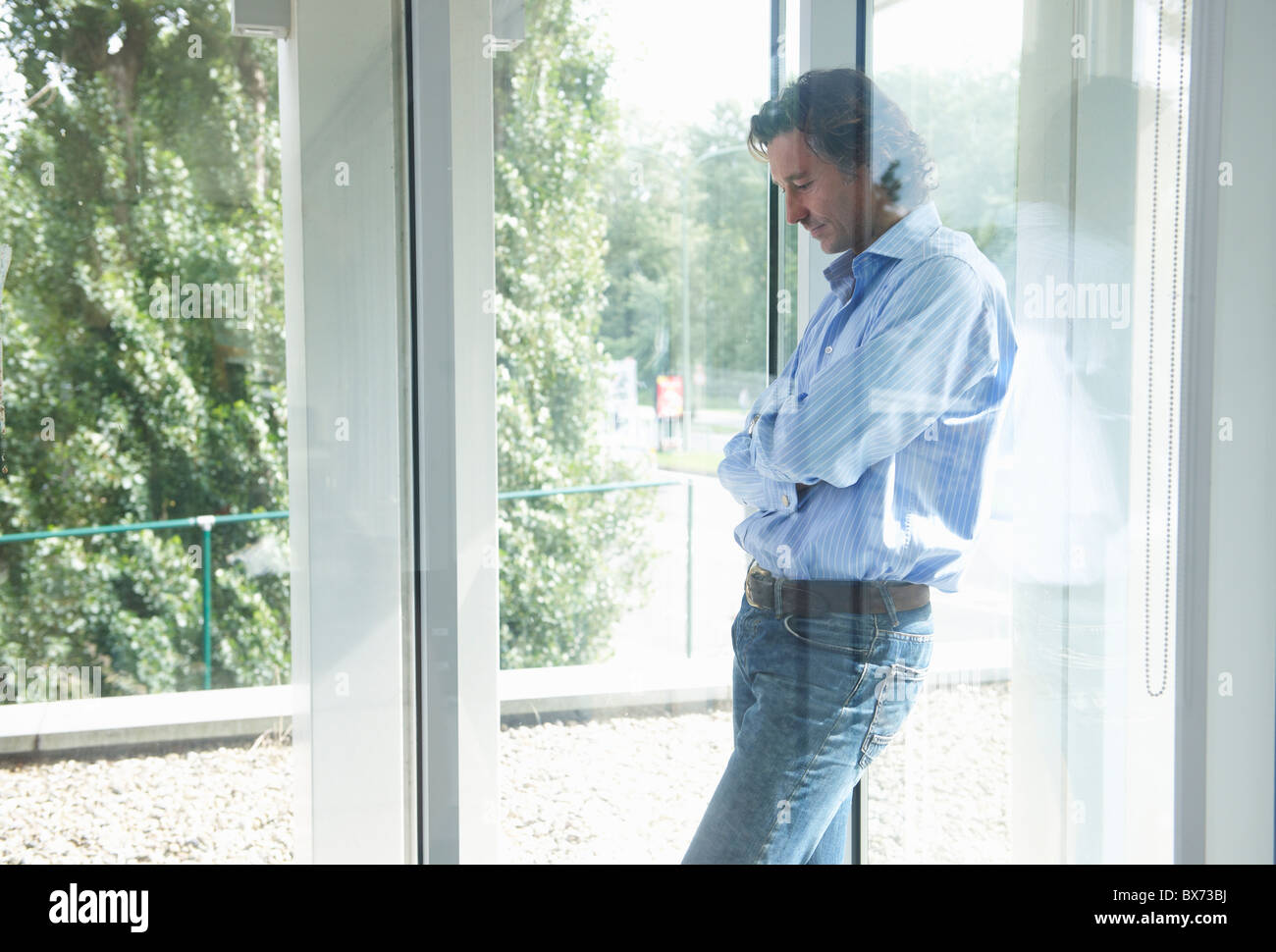 Man leaning on office windows, thinking Stock Photo - Alamy