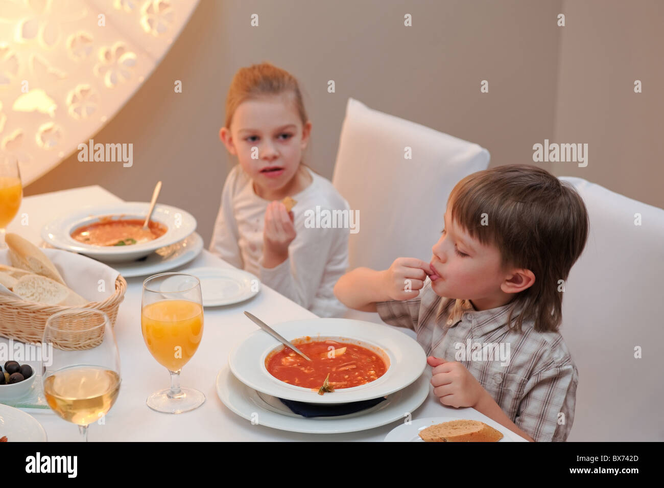 Sister and brother enjoying meal sitting at restaurant table. Boy in ...