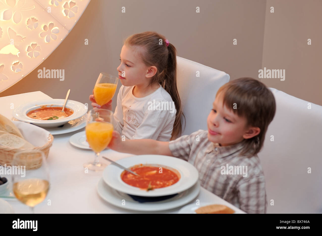 Sister and brother enjoying meal sitting at restaurant table. Girl in ...