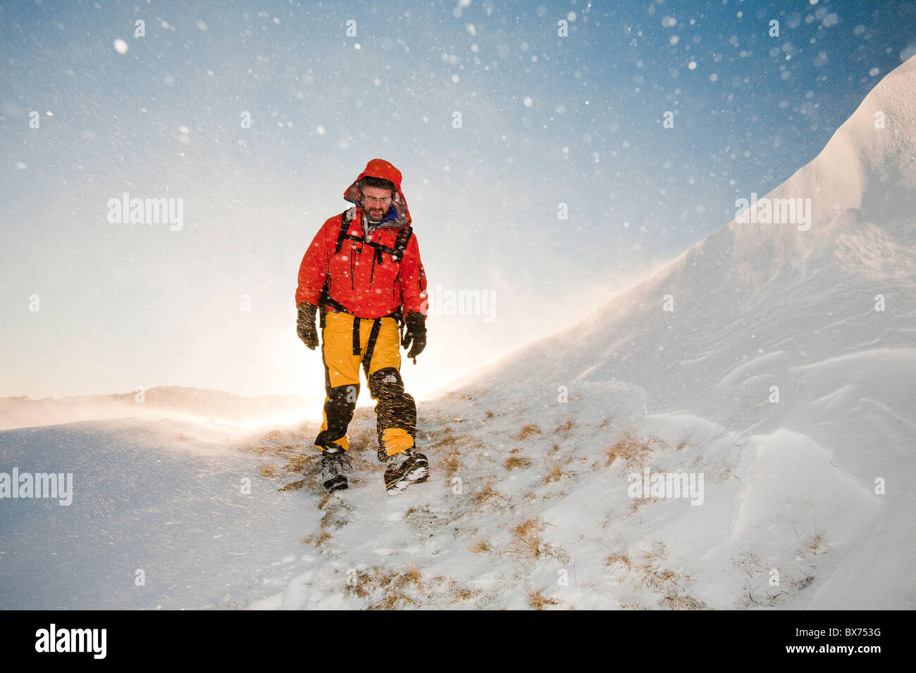 A climber being blasted by spindrift during high winds moving snow ...