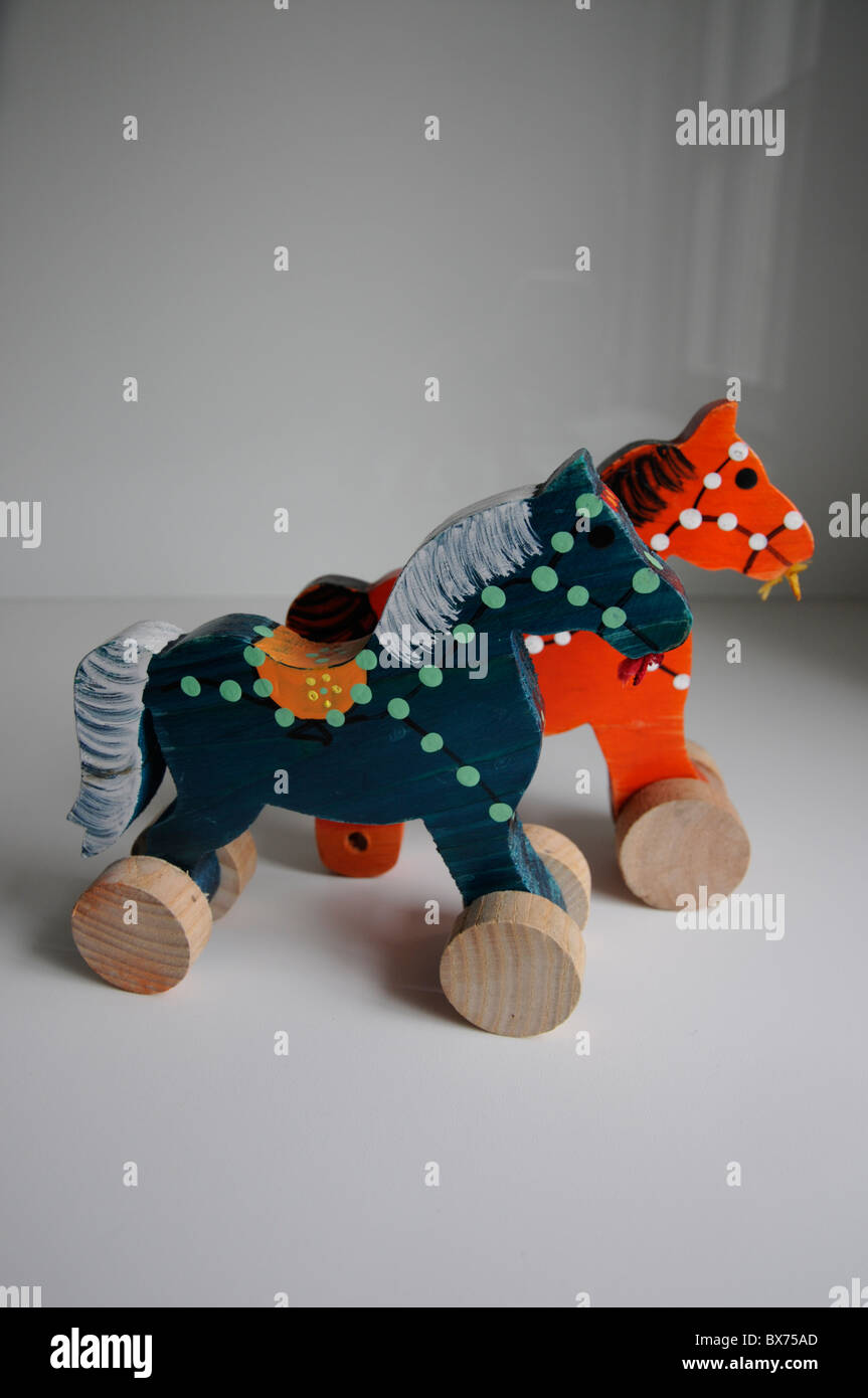 Two children's toy wooden horses, painted in bright colours on top of ...