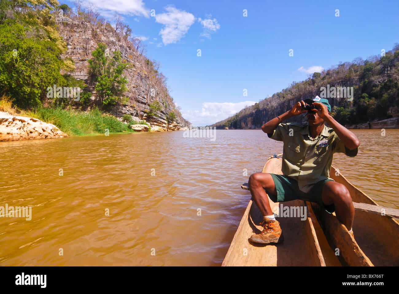 Guide looking out for birds on the Manambolo River, Tsingy de Bemaraha ...