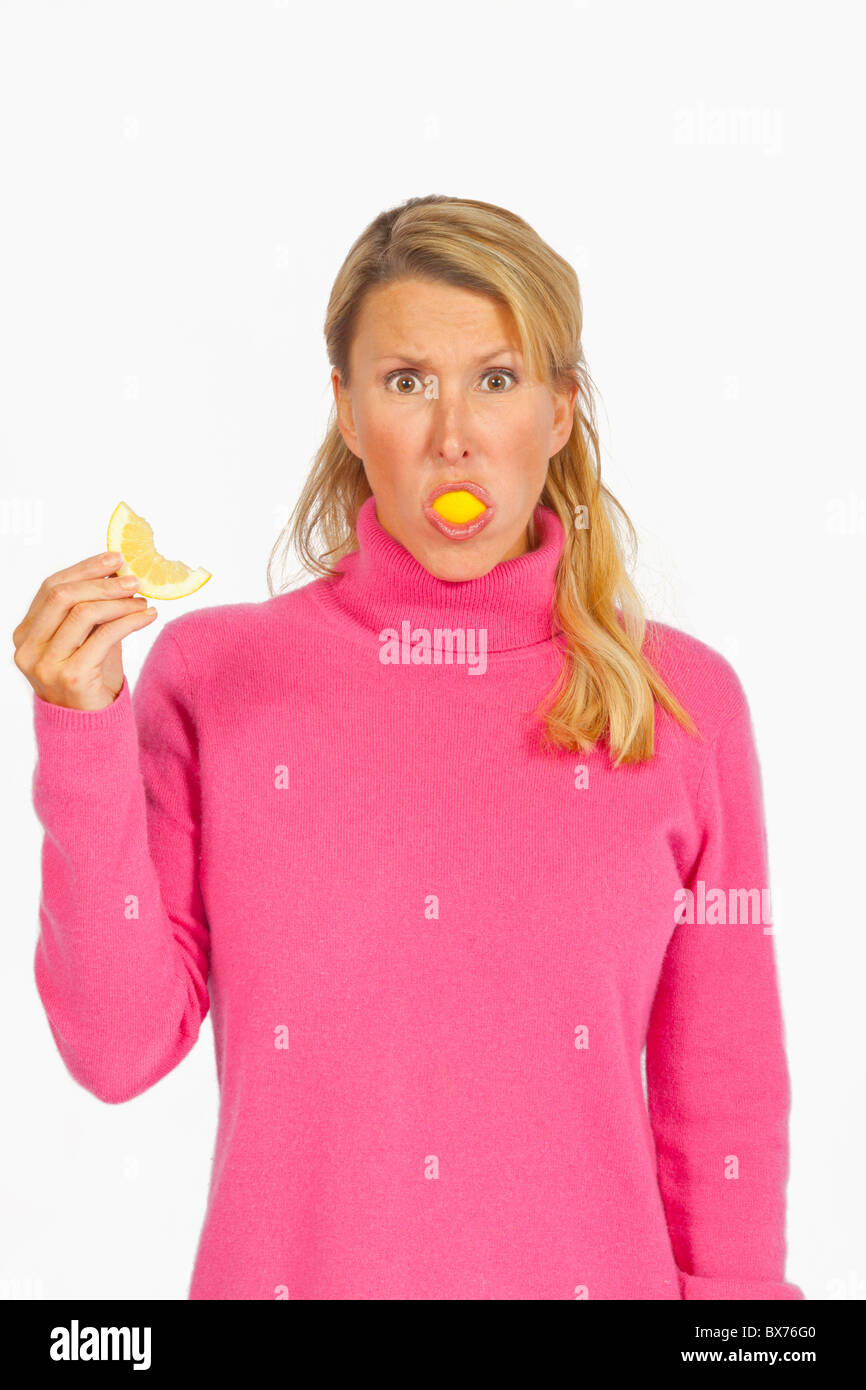 Woman takes a whole lemon into her mouth with a look of surprise Stock ...