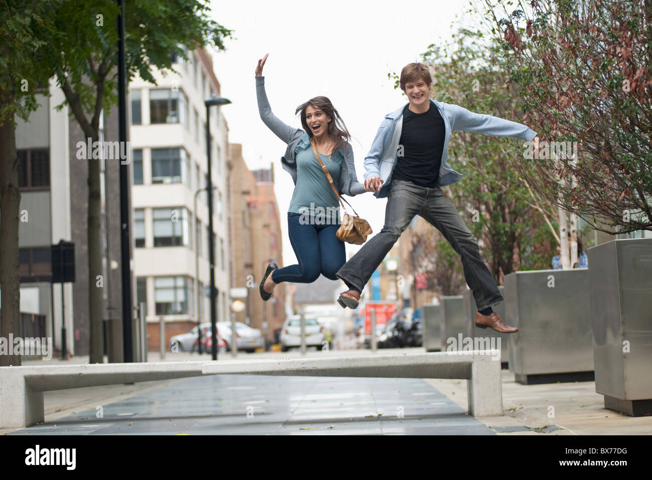 Young couple jumping in street Stock Photo - Alamy