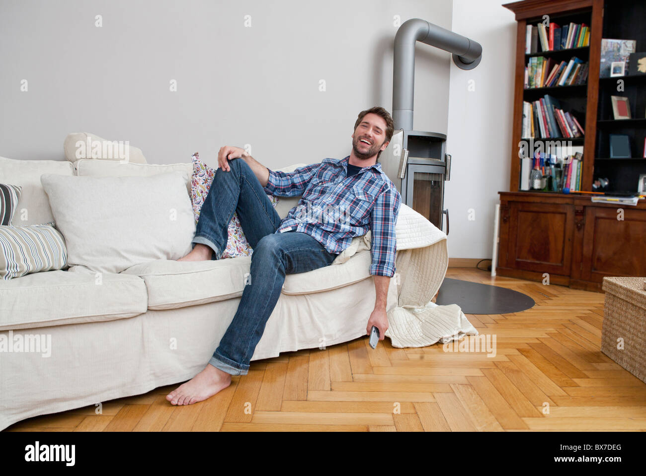 Man sitting on couch Stock Photo - Alamy