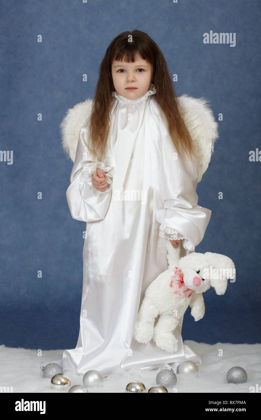 Little girl dressed as an angel with a rabbit on a blue background ...