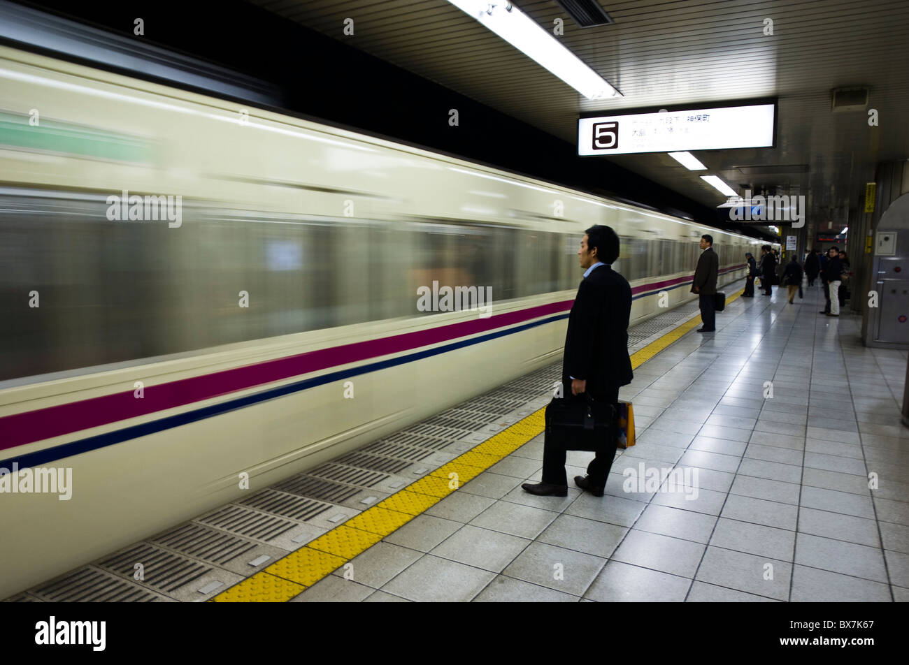 man in front of arriving metro train in tokyo, japan Stock Photo - Alamy