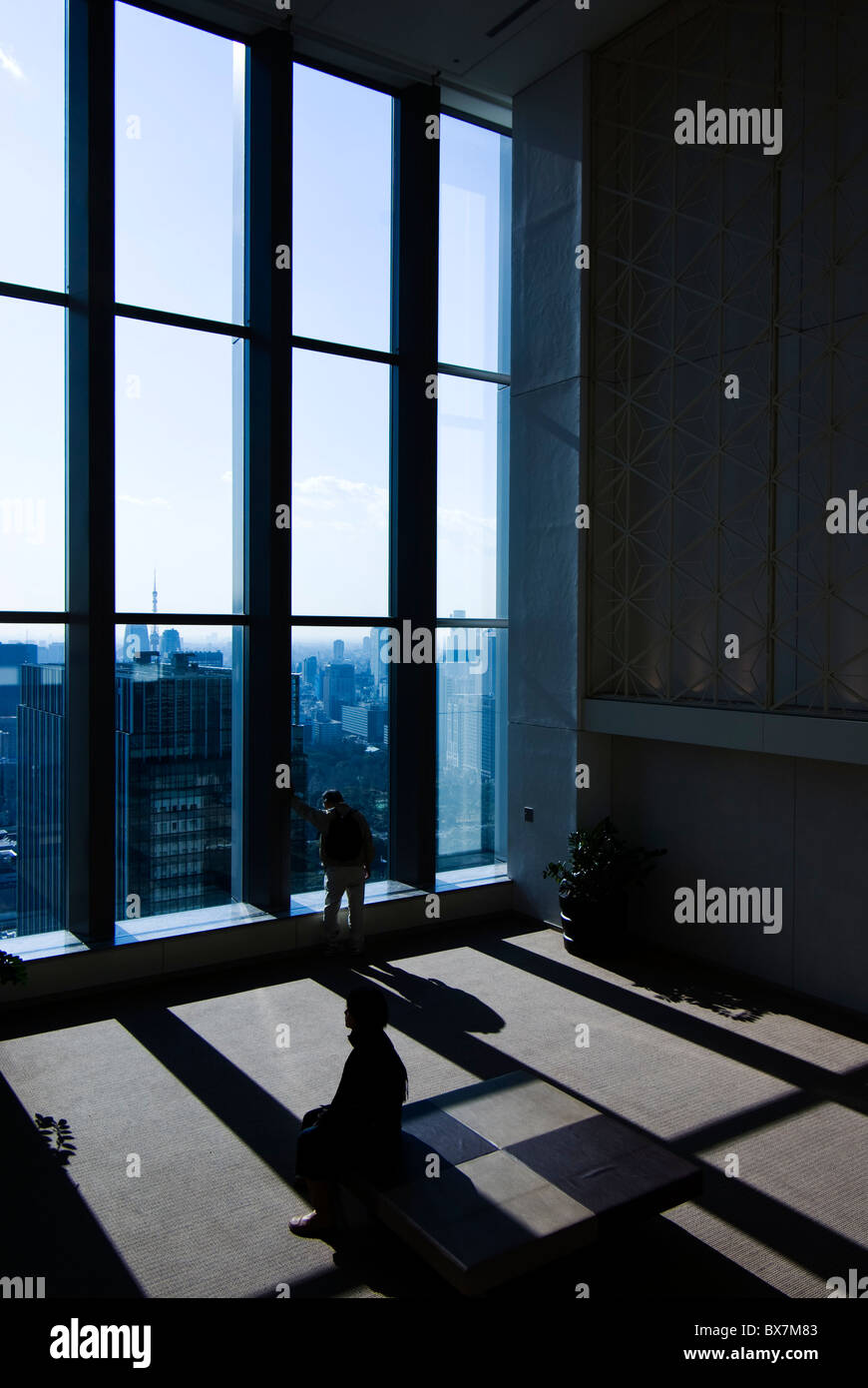 man looking out the giant windows at the marunouchi building ...