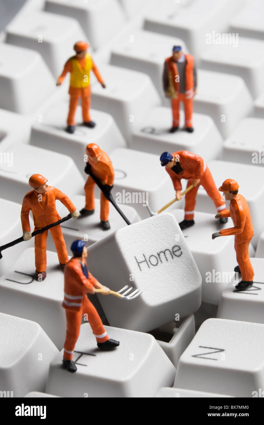 Worker figurines posed around the Home key on a computer keyboard Stock ...