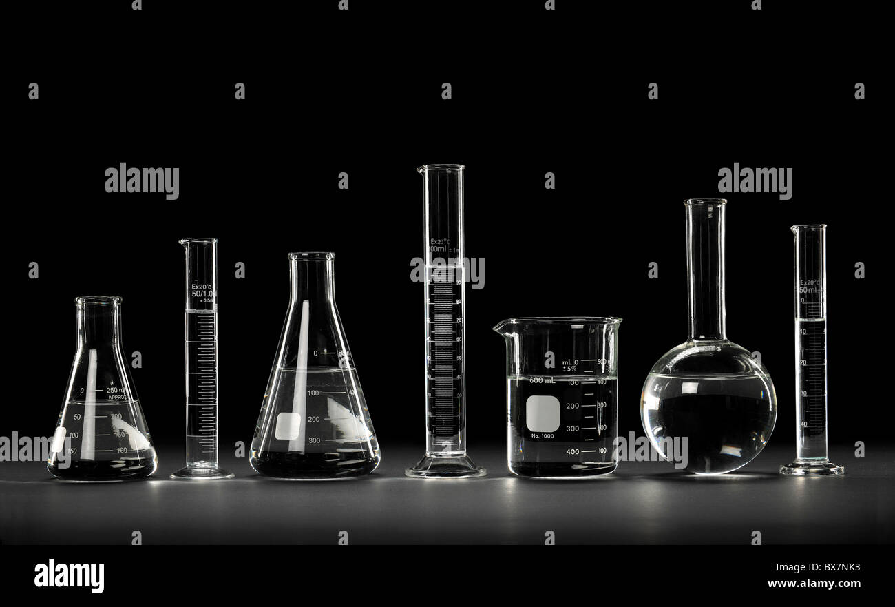 Laboratory glassware over black background and reflections on table ...