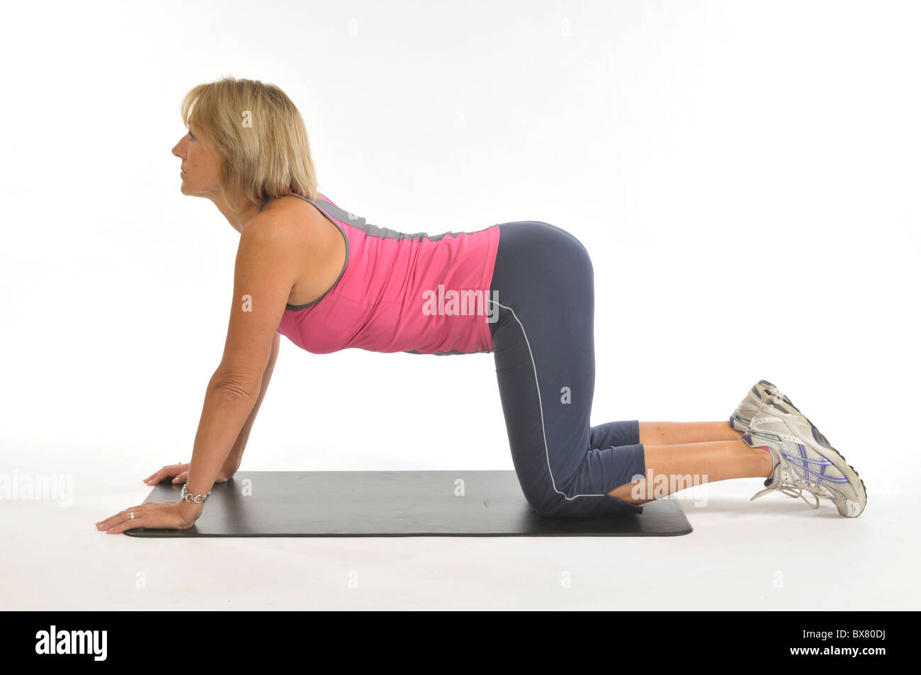 Fifty year old women doing a cat stretch on a mat in studio Stock Photo ...
