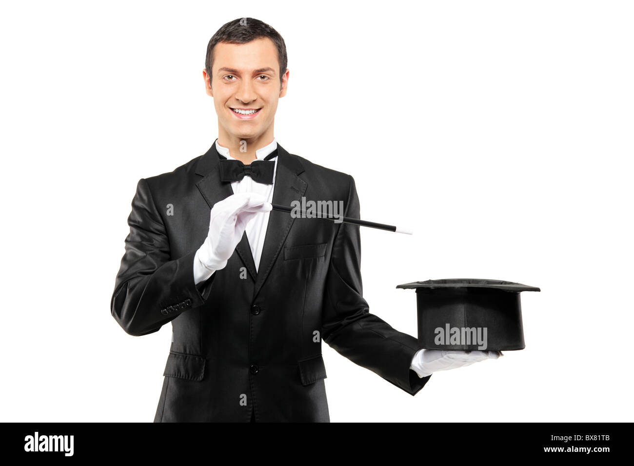 A magician in a black suit holding an empty top hat and magic wand ...