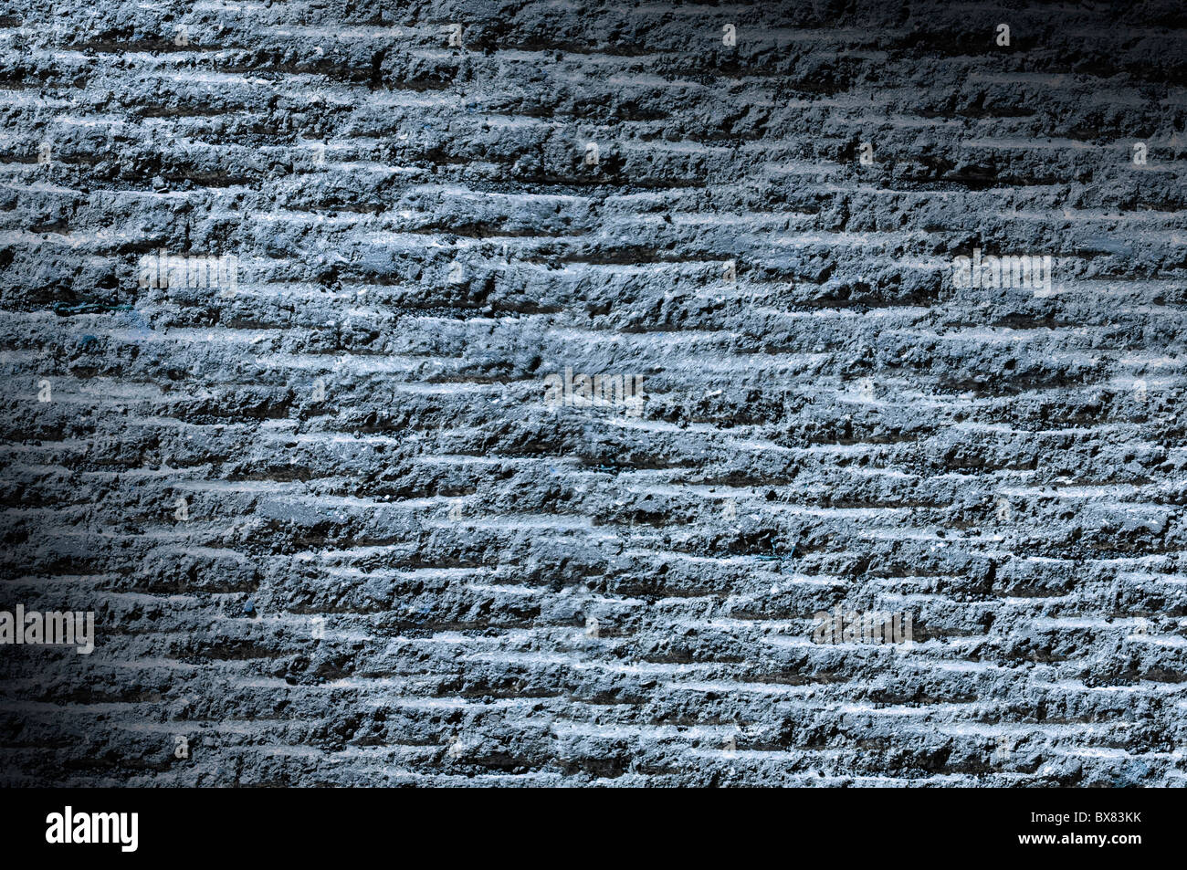 Grooved asphalt or rock surface texture lit diagonally with blue light ...