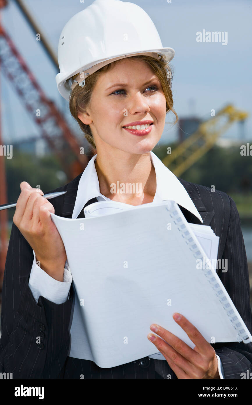 Portrait of beautiful engineer holding architectural project and pen ...