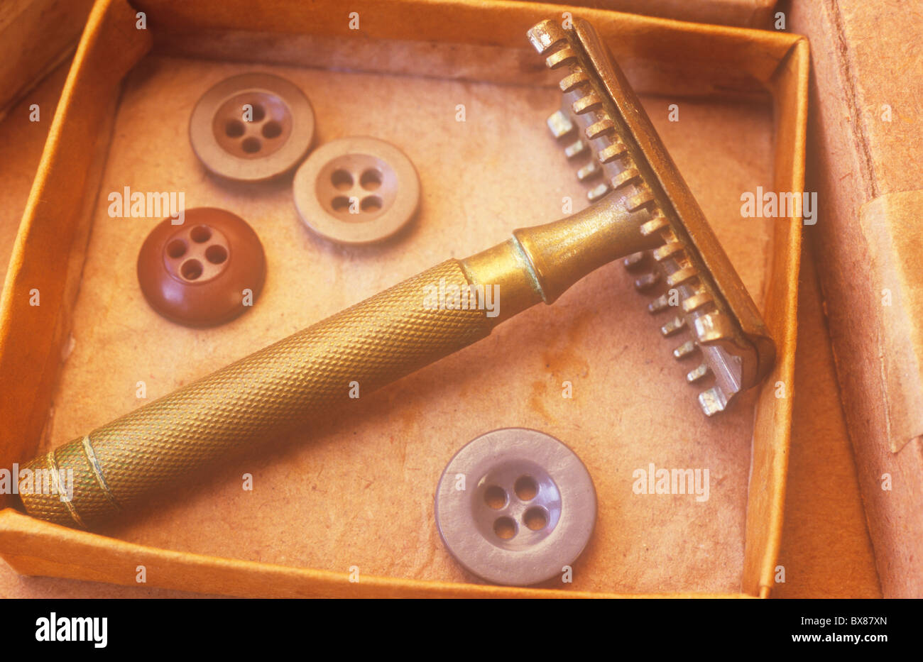 Worn safety razor lying with four male brown or grey buttons in small ...